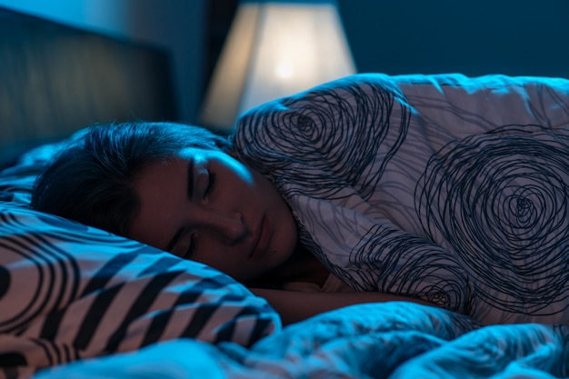 Joven mujer durmiendo en una cama en un dormitorio oscuro | Foto Premium Joven mujer durmiendo en una cama en un dormitorio oscuro | Foto Premium