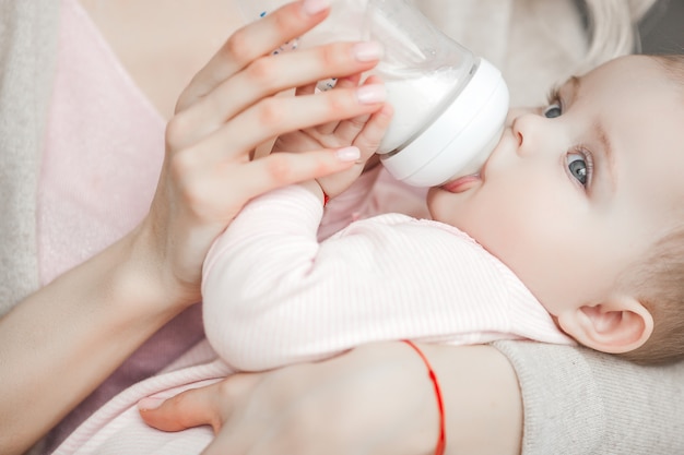 Madre Joven Que Alimenta A Su Pequeña Hija Linda Del Bebé Con La Botella De Fórmula Infantil