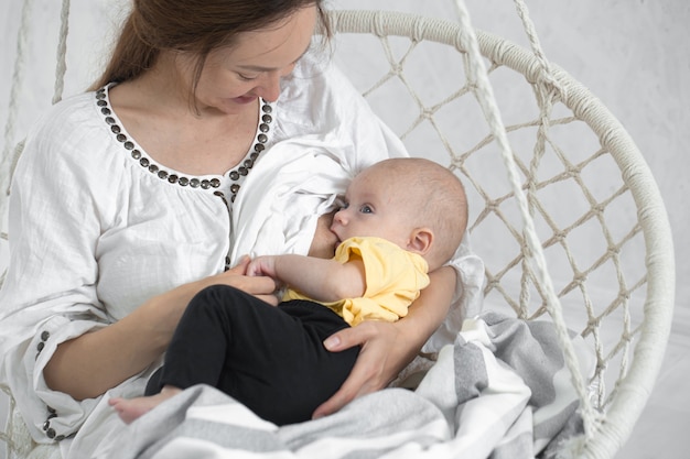 Mamá Feliz Alimenta Al Bebé En Una Hamaca Blanca Concepto De Maternidad Feliz Foto Premium
