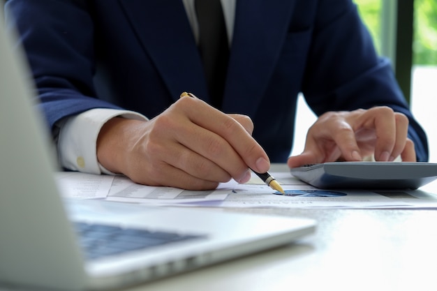 La mano del hombre de negocios trabaja en una calculadora y utiliza una ... La mano del hombre de negocios trabaja en una calculadora y utiliza una ...