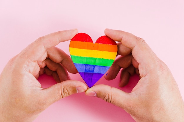 Manos sujetando un corazón con los colores de la bandera del orgullo ... Manos sujetando un corazón con los colores de la bandera del orgullo ...