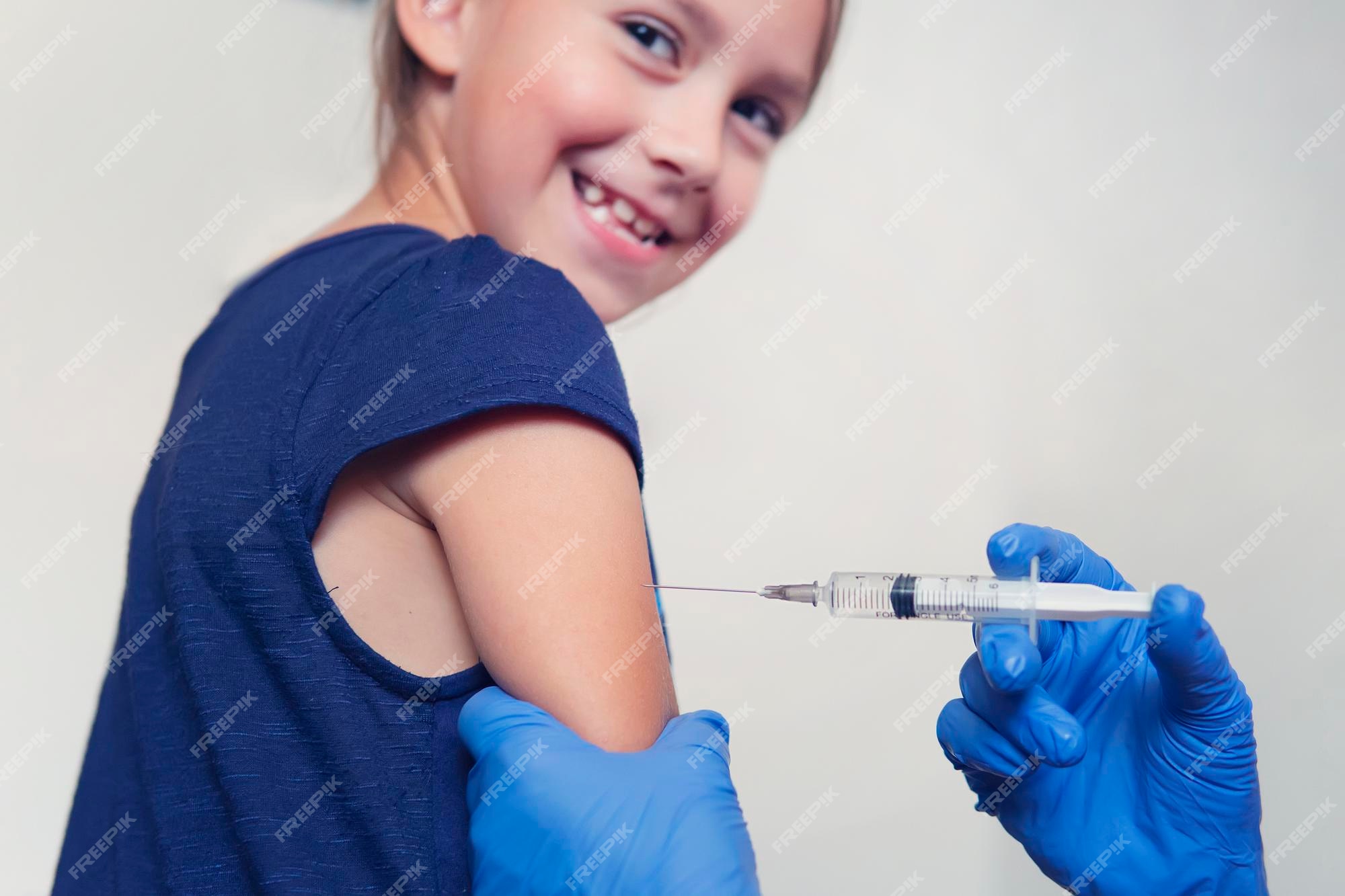 Un Médico Poniendo Una Inyección A Un Niño La Niña Sonríe Y Se Ríe No Tiene Miedo De