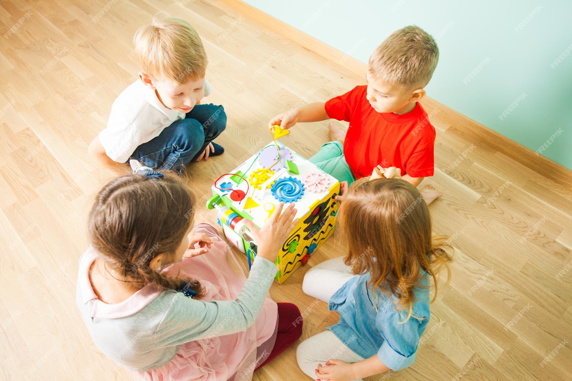 Los Niños Y Niñas En Edad Preescolar Juegan En El Suelo De Madera Con