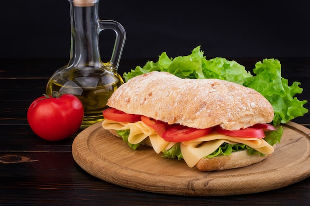 Sándwich de chapata con lechuga, jamón serrano y queso sobre tabla de ... Sándwich de chapata con lechuga, jamón serrano y queso sobre tabla de ...