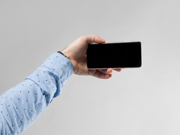 Close-up da mão do homem segurando o smartphone horizontalmente em ... Close-up da mão do homem segurando o smartphone horizontalmente em ...