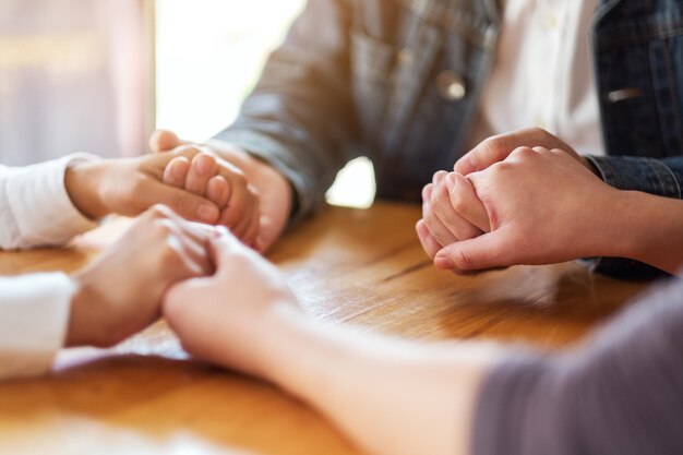 Grupo de pessoas sentadas em círculo de mãos dadas e orando juntas ou ... Grupo de pessoas sentadas em círculo de mãos dadas e orando juntas ou ...