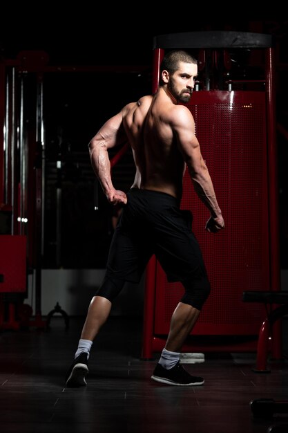Jovem Em Pé Forte Na Academia E Flexionando Os Músculos Muscular