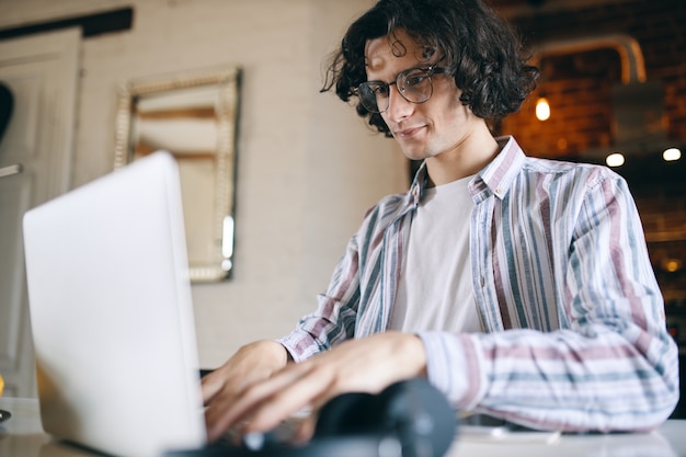 Jovem programador de computador habilidoso em óculos, digitando em um ... Jovem programador de computador habilidoso em óculos, digitando em um ...