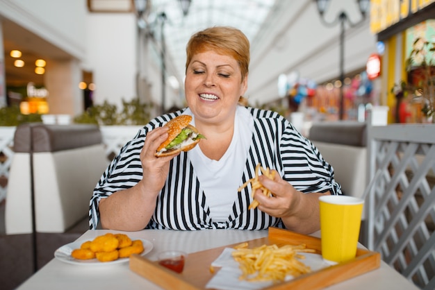 Mulher gorda comendo alimentos de alto teor calórico em restaurante de ... Mulher gorda comendo alimentos de alto teor calórico em restaurante de ...