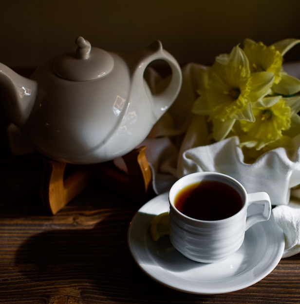 Eine tasse schwarzen tee in der weißen tasse neben weißem teekanne ... Eine tasse schwarzen tee in der weißen tasse neben weißem teekanne ...