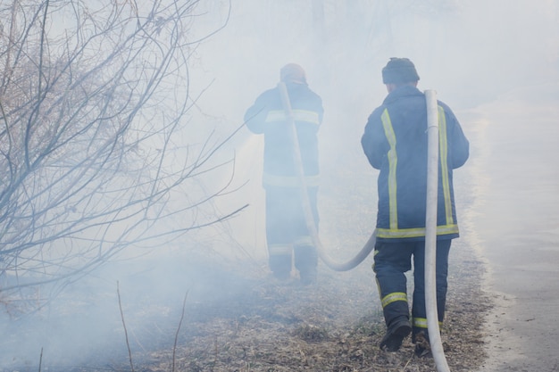 Feuerwehrmann zwei im rauchkampf-waldbrand. tapferer feuerwehrmann geht ... Feuerwehrmann zwei im rauchkampf-waldbrand. tapferer feuerwehrmann geht ...