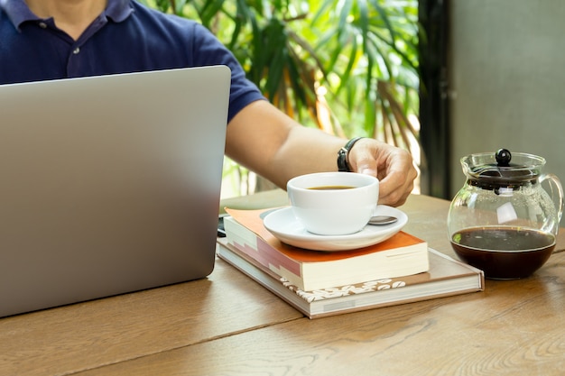 Premium Photo | Businessman holding cup of coffee while working on laptop. Premium Photo | Businessman holding cup of coffee while working on laptop.