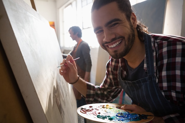 Close up portrait of smiling man painting on artists canvas | Premium Photo Close up portrait of smiling man painting on artists canvas | Premium Photo