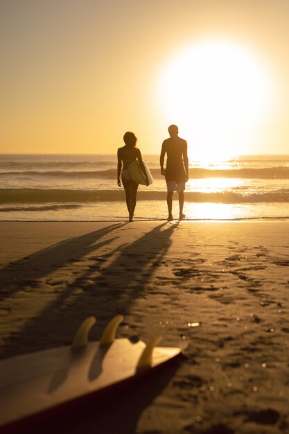 Free Photo Couple Walking Together With Surfboard On The Beach