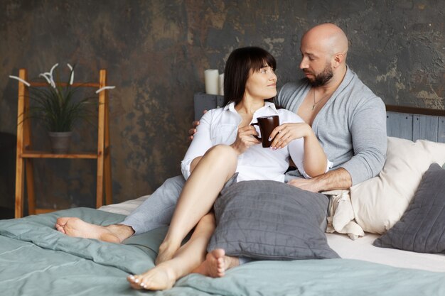 Premium Photo Cute Young Couple Drinking Morning Coffee Lying In Bed