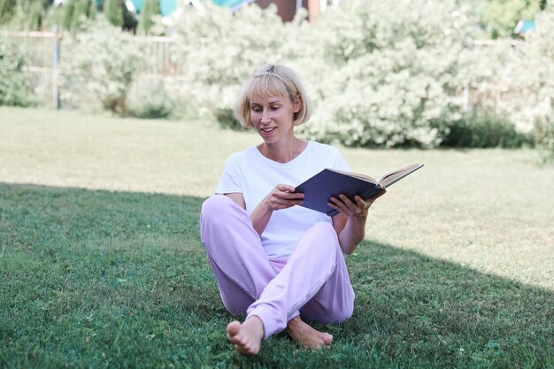 Premium Photo Cute Young Woman Sitting On The Grass And Reading The Book