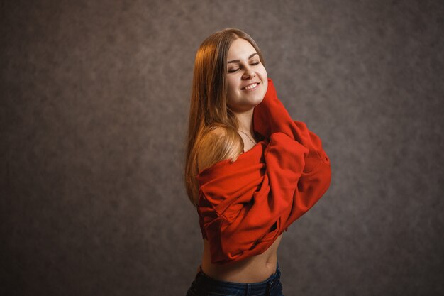 Premium Photo Girl Tries On A Red Sweater On A Gray Background