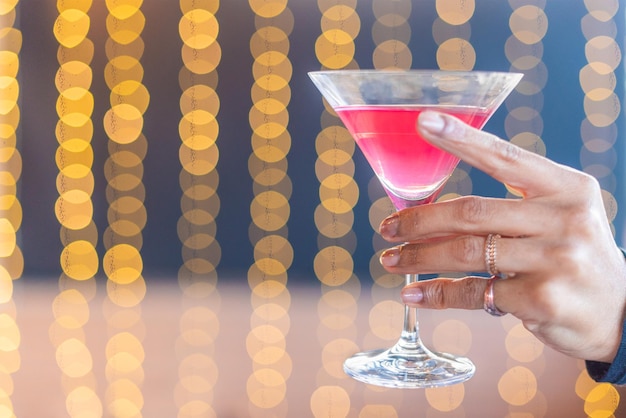 Premium Photo A Hand Holding A Glass With A Red Cocktail On Blurred
