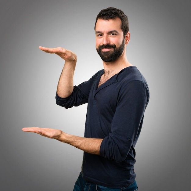 Premium Photo Handsome Man With Beard Holding Something On Grey