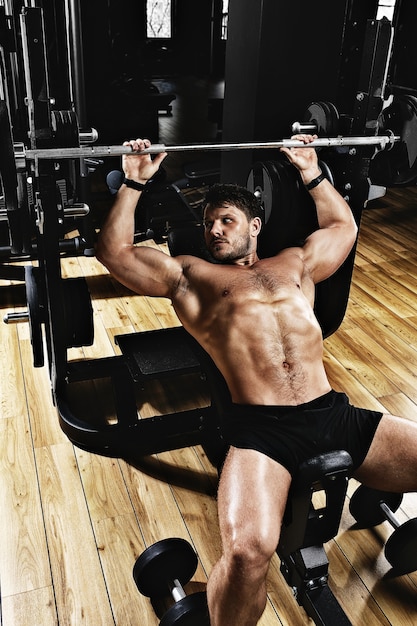 Premium Photo Handsome Young Man Doing Bench Press Workout In Gym