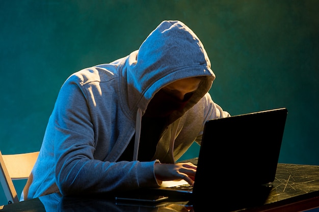 Free Photo | Hooded computer hacker stealing information with laptop Free Photo | Hooded computer hacker stealing information with laptop