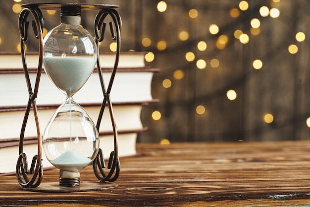 Premium Photo Hourglass On Wooden Desk Against Blurred Lights