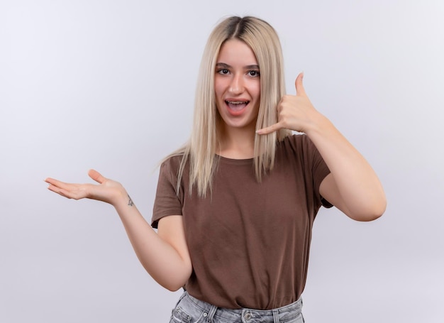 Free Photo Joyful Young Blonde Girl In Dental Braces Doing Call Gesture And Showing Empty Hand