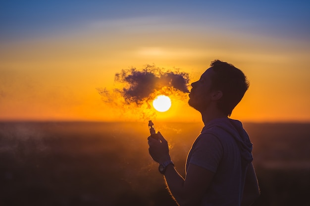 Premium Photo The Man Smoke An Electronic Cigarette On The Sunset