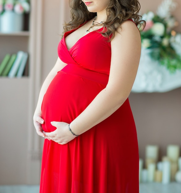Premium Photo A Pregnant Woman With Dark Hair In A Red Dress Hugs Her