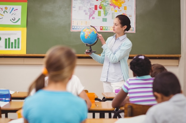 Premium Photo | Pupils listening to their teacher holding globe Premium Photo | Pupils listening to their teacher holding globe