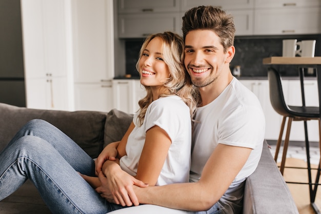 Free Photo Smiling Attractive Couple Sitting On Sofa Hugging Each