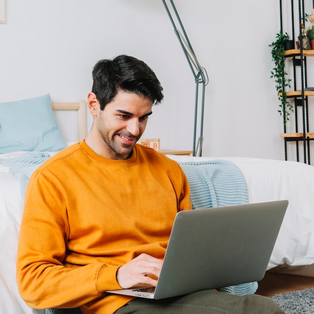 Free Photo | Smiling man using laptop near bed Free Photo | Smiling man using laptop near bed