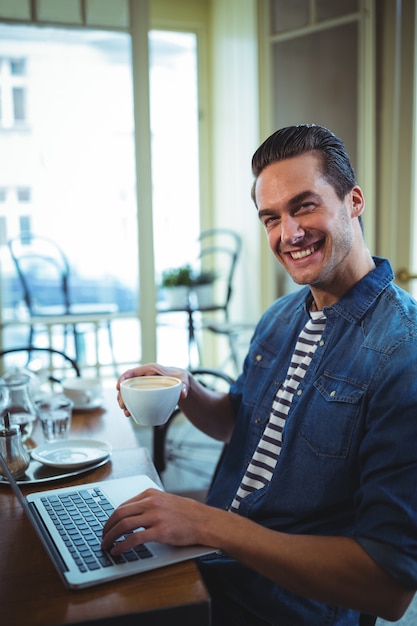 Free Photo | Smiling man using laptop while having coffee in cafã© Free Photo | Smiling man using laptop while having coffee in cafã©