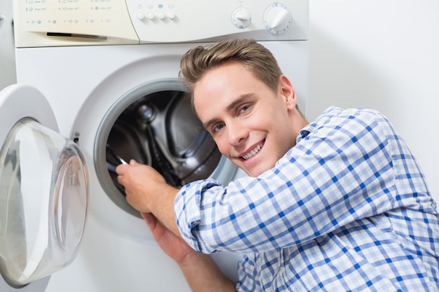 Premium Photo | Smiling technician repairing a washing machine Premium Photo | Smiling technician repairing a washing machine