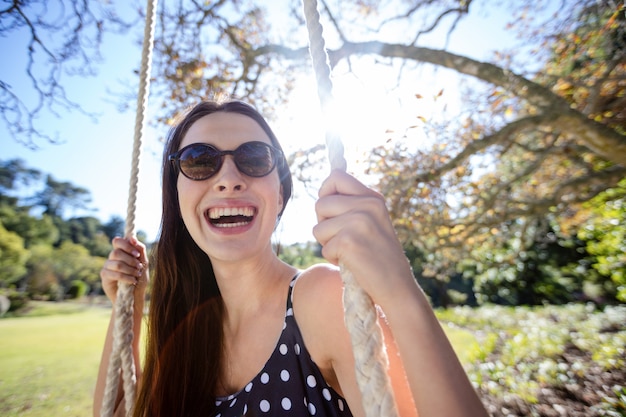 Premium Photo Smiling Woman Sitting On Swing In Park