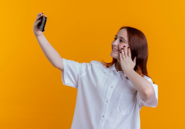 Free Photo Smiling Young Redhead Girl Take A Selfie And Putting Hand
