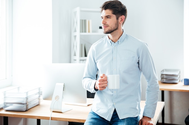 Premium Photo | Thoughtful young man drinking coffee and thinking in office Premium Photo | Thoughtful young man drinking coffee and thinking in office