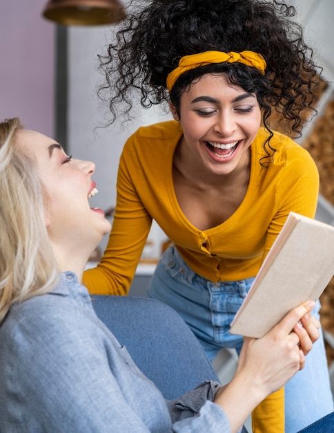 Free Photo | Two women laughing while reading book Free Photo | Two women laughing while reading book