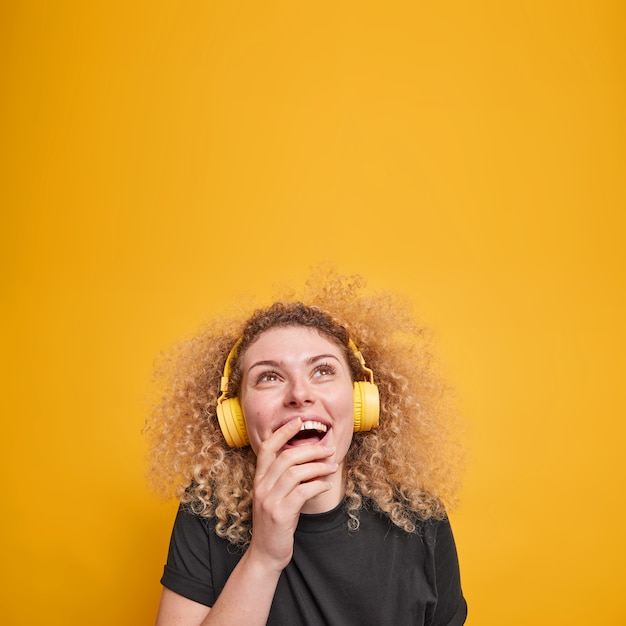 Free Photo Vertical Shot Of Overjoyed Curly Haired Woman Looks Above