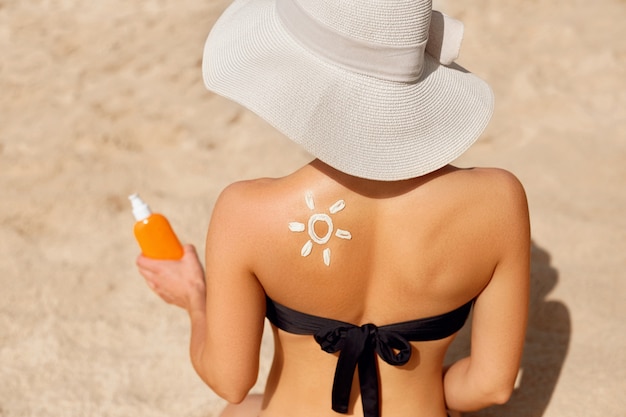 Premium Photo Woman Applying Sun Cream On Tanned Shoulder In Form Of