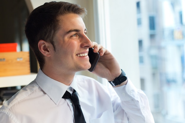Free Photo | Young businessman using his mobile phone in office. Free Photo | Young businessman using his mobile phone in office.