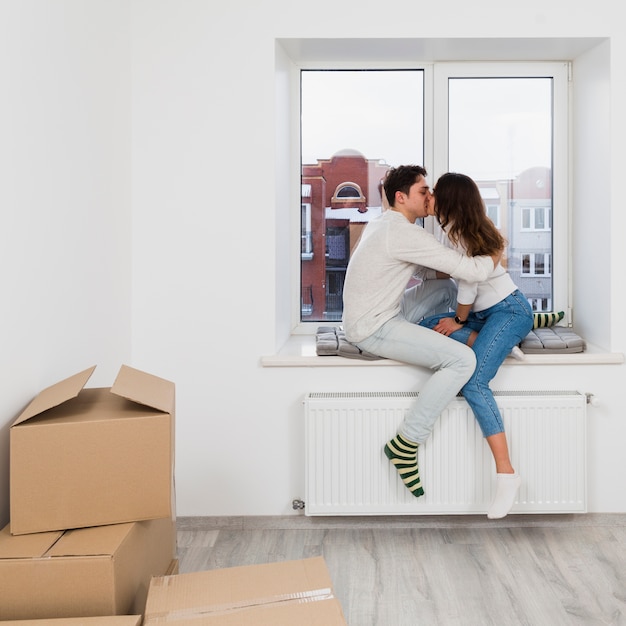 Free Photo Young Couple Sitting On Window Sill Kissing Each Other In