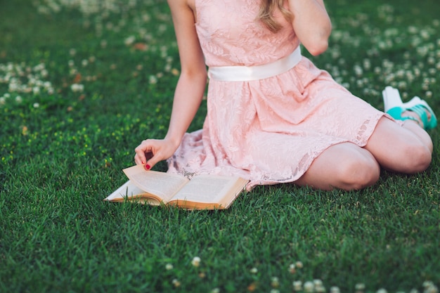 Premium Photo A Young Girl Sitting On The Grass And Reading A Book
