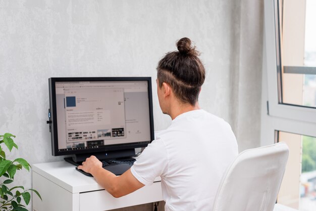 Premium Photo | Young hipster using computer sitting at loft space. programmer typing data code ...