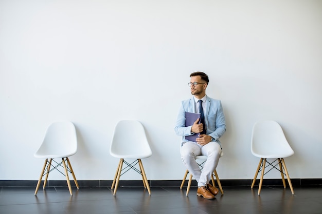 Premium Photo | Young man sitting in the waiting room with a folder in ... Premium Photo | Young man sitting in the waiting room with a folder in ...