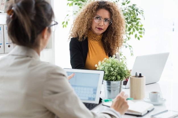 Deux Femmes D'affaires Travaillant Avec Un Ordinateur Portable Dans Son ... Deux Femmes D'affaires Travaillant Avec Un Ordinateur Portable Dans Son ...