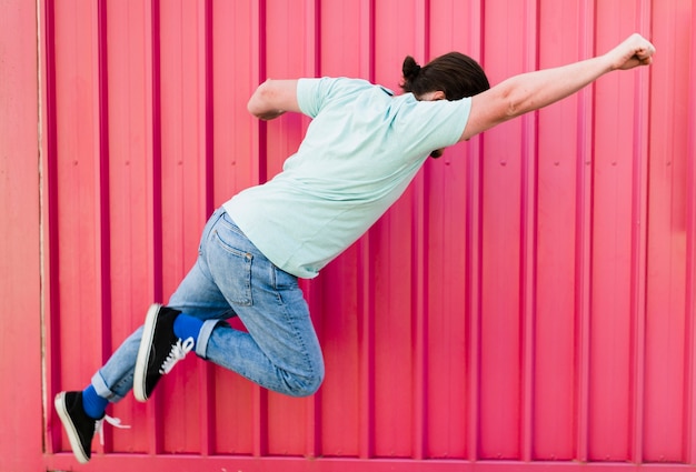 Homme Volant Avec Les Bras Levés Contre Le Mur Ondulé Rose | Photo Gratuite Homme Volant Avec Les Bras Levés Contre Le Mur Ondulé Rose | Photo Gratuite